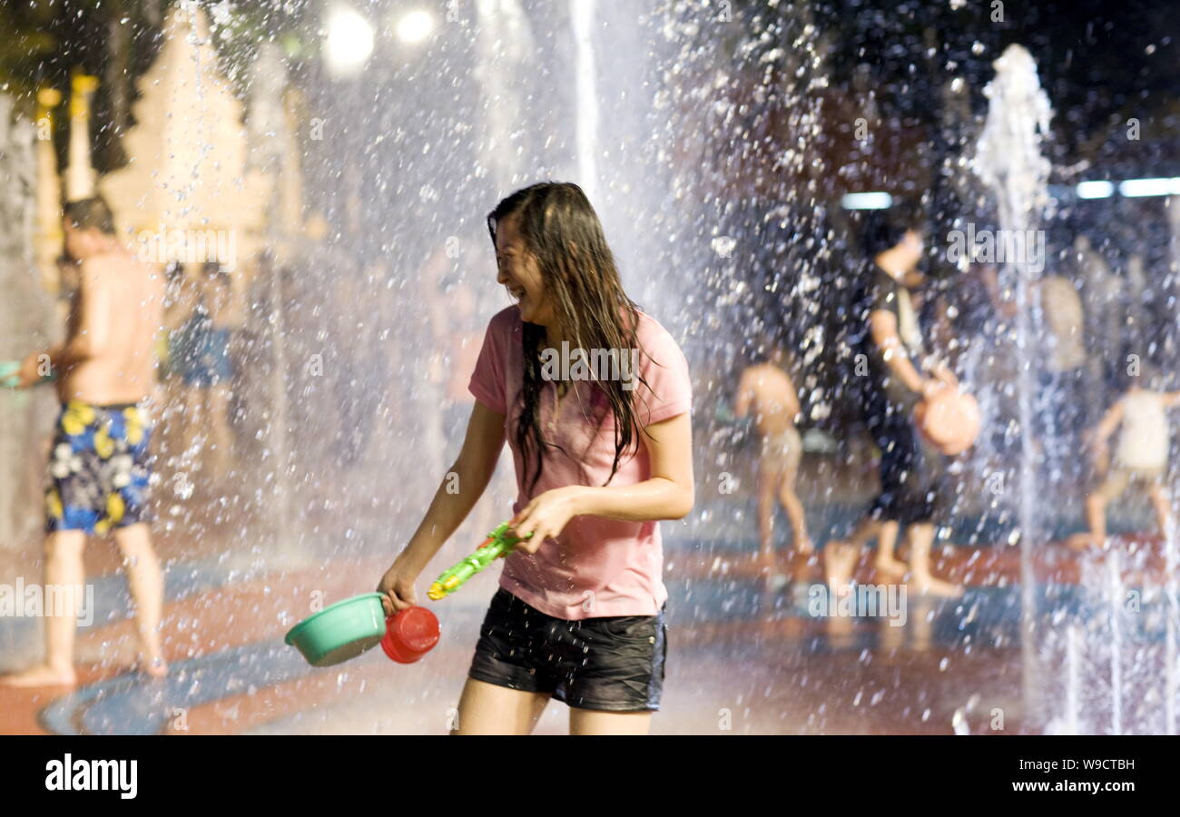 Chinese tourists and local citizens splash water during a water ...