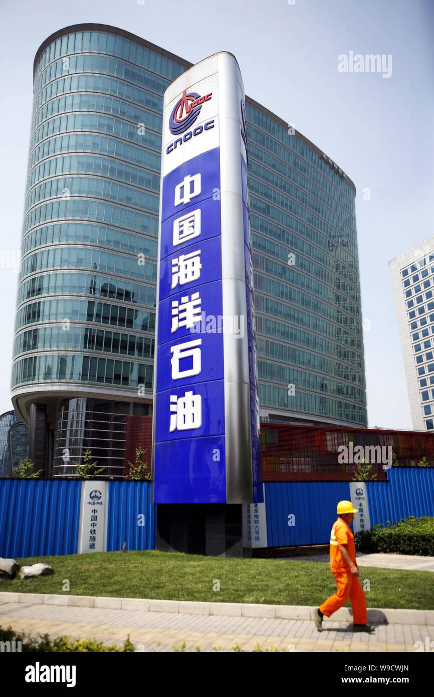 A Chinese worker walks past the headquarters of CNOOC (China National ...
