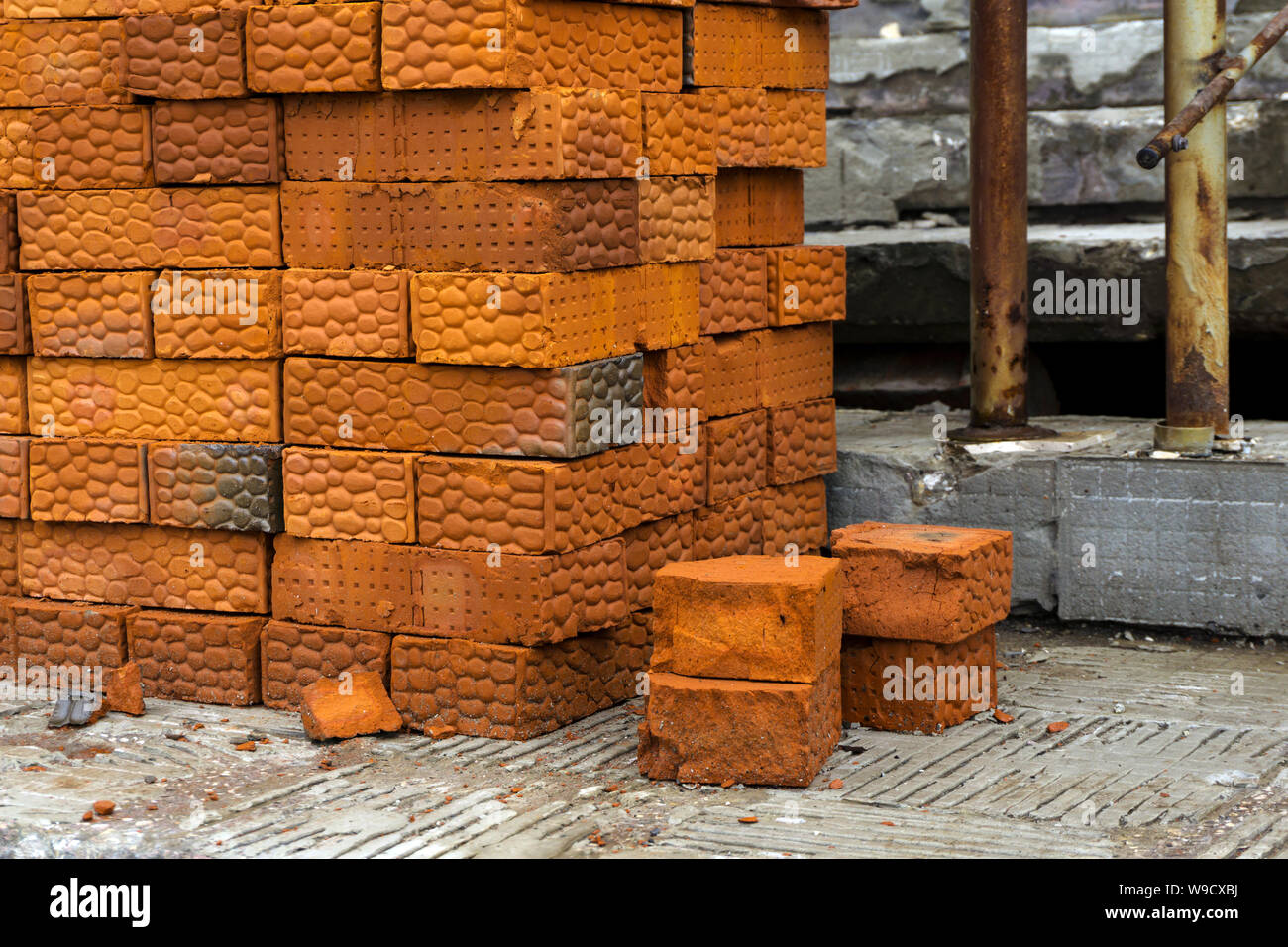 stack of bricks made of red clay on the background of some structures ...