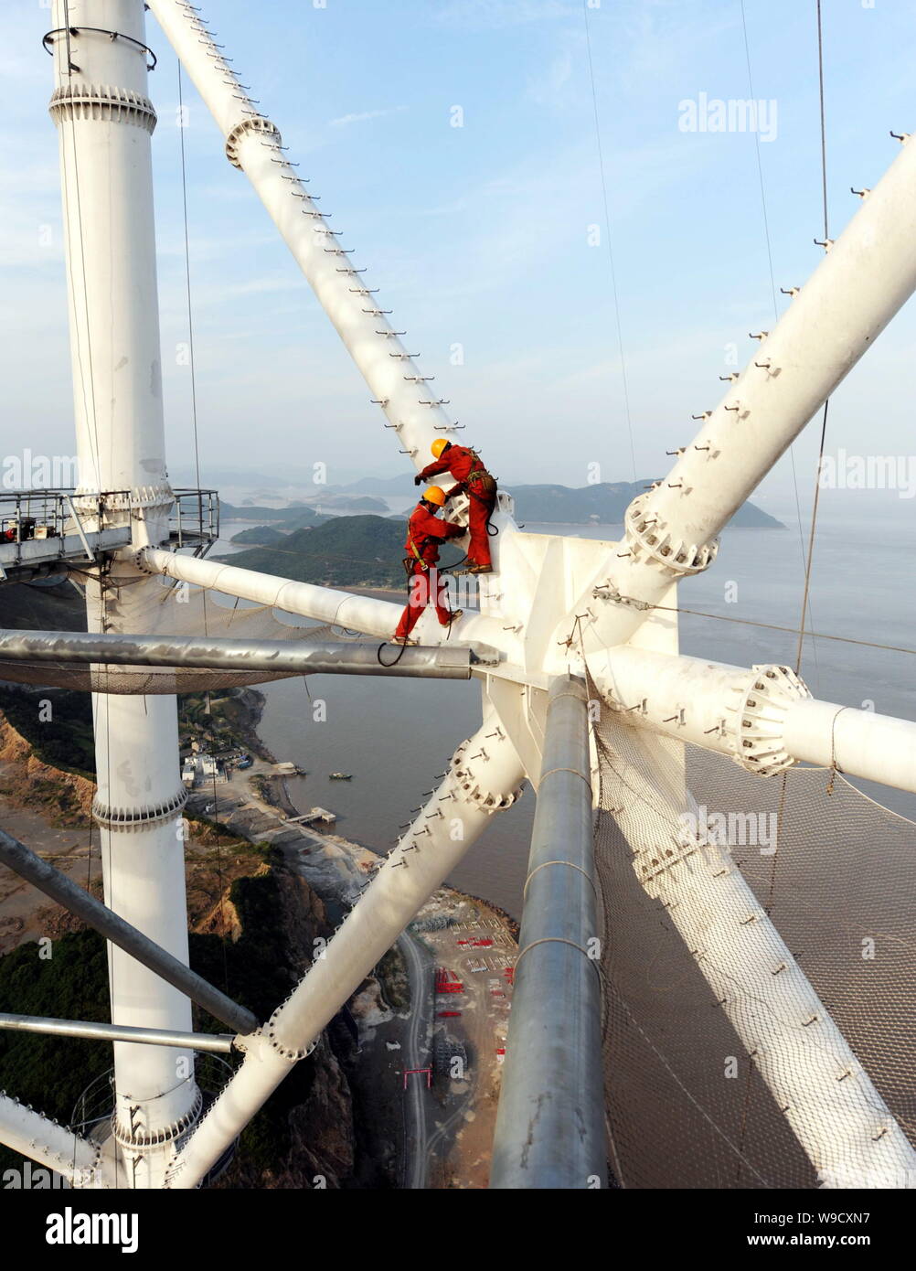 Chinese construction workers are seen on a 370-meter-tall pylon under ...