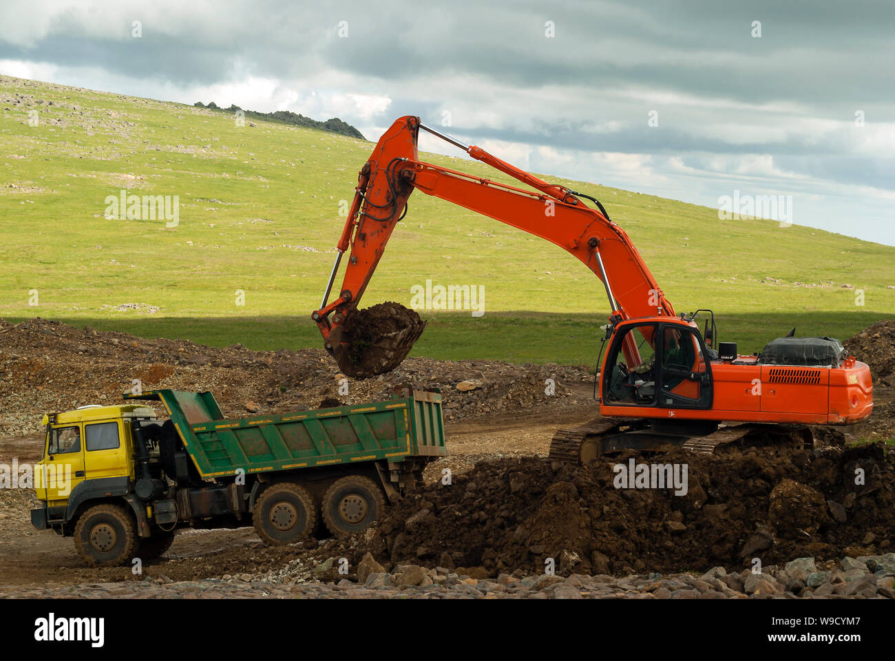 laying a road in a mountainous area, an excavator and a dumper during ...