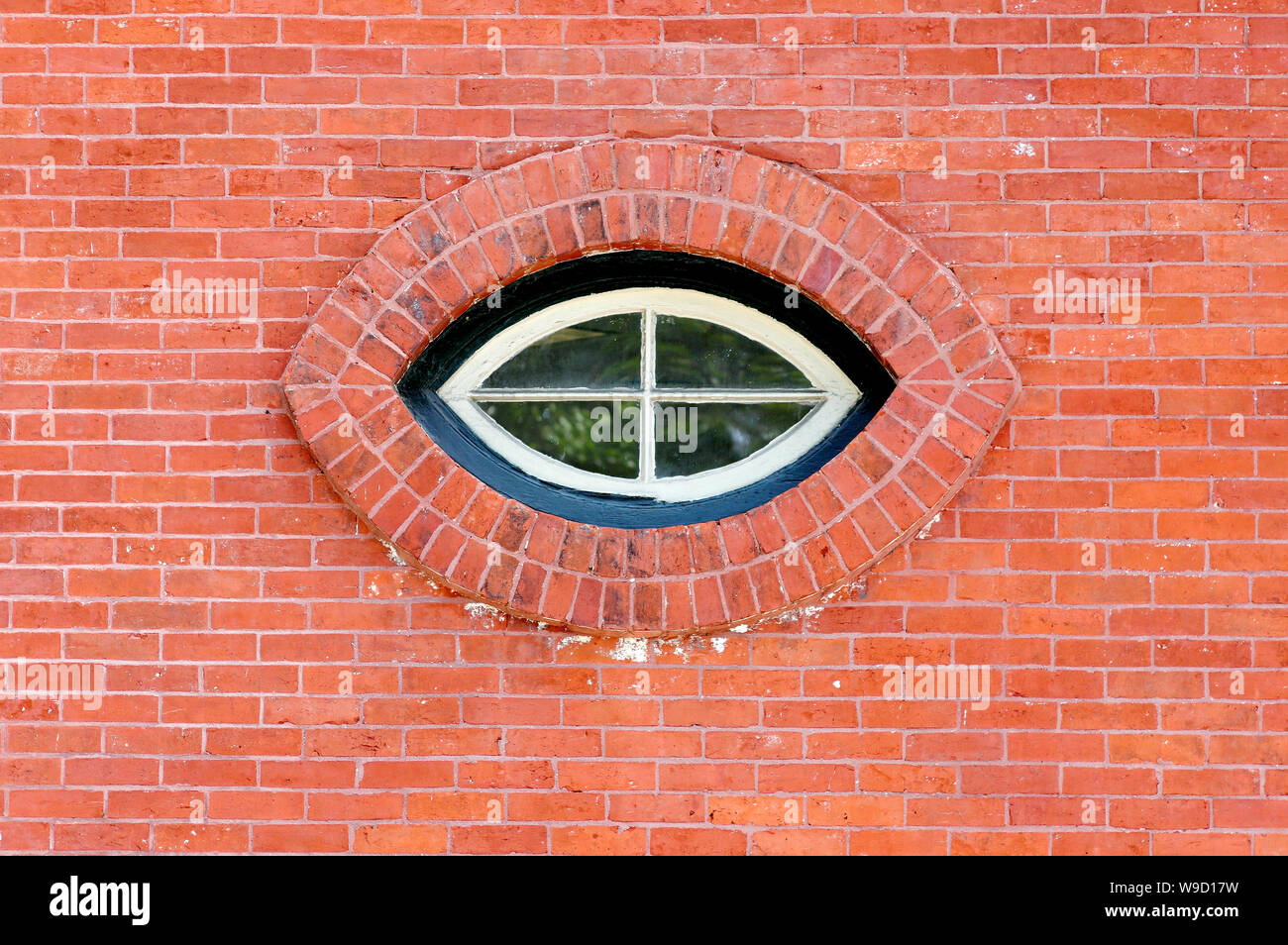 Cat eye shaped window in a red brick wall Stock Photo - Alamy