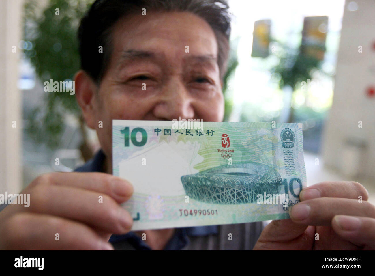 A Chinese man shows a 10-yuan (US$1.43) commemorative Olympic banknote ...