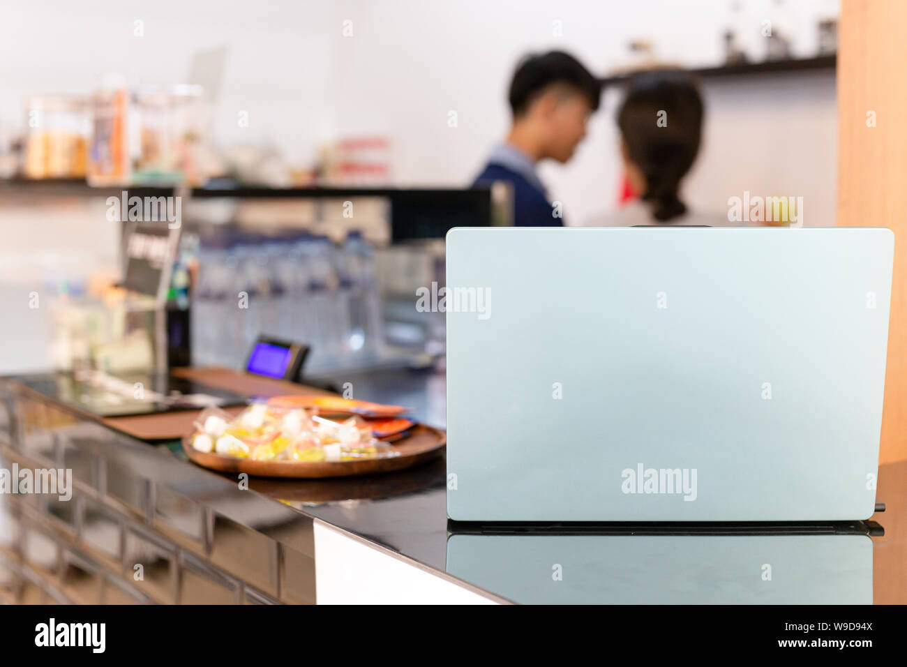 Laptop on counter coffee bar with barista working in bur background ...
