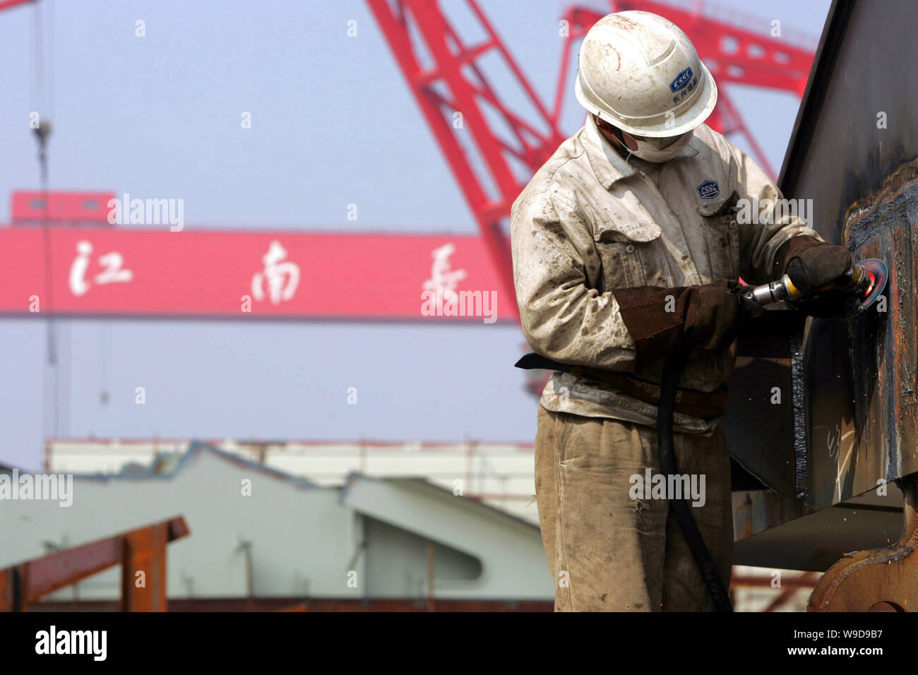 A Chinese factory worker polishes a ship under construction at a ...