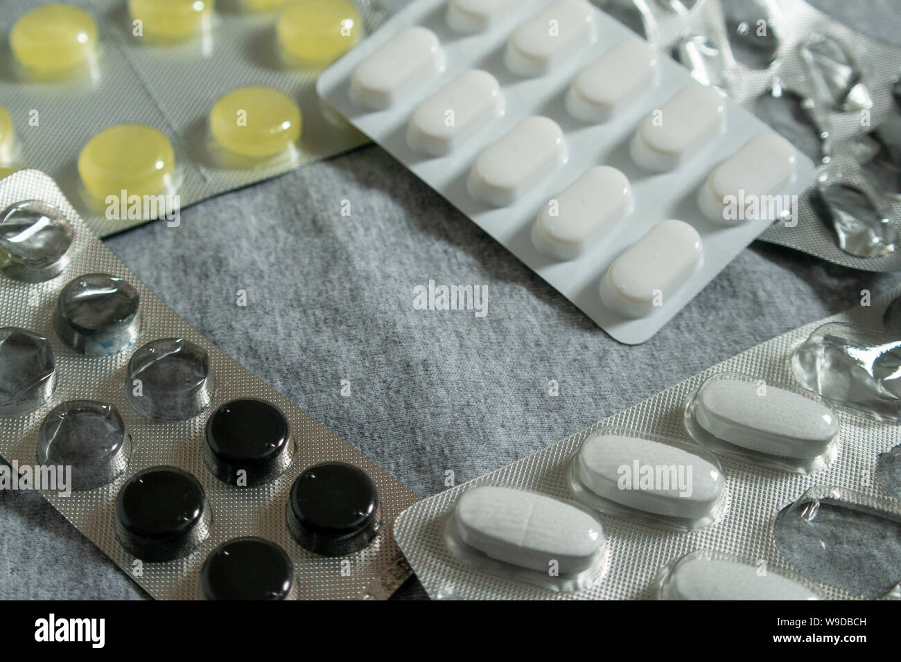 Blister packs of various pills and pastilles on the gray background ...