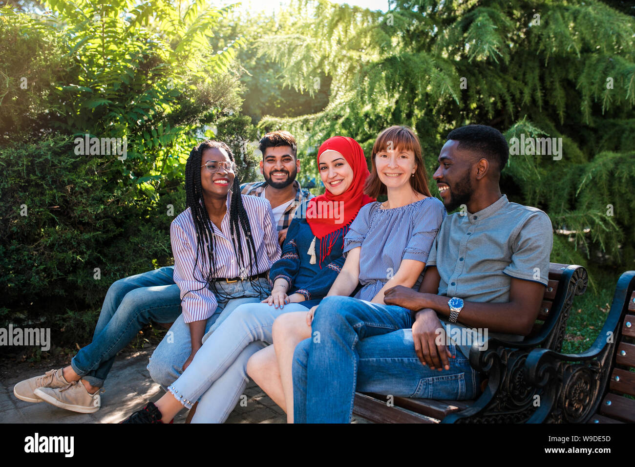 Multiracial young friends sitting by the street and having fun Stock ...