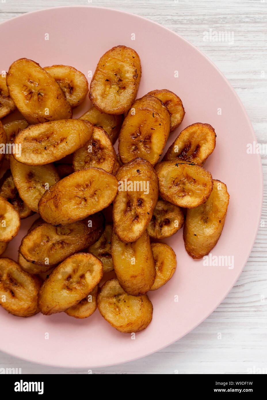 Homemade fried plantains on a pink plate on a white wooden background ...