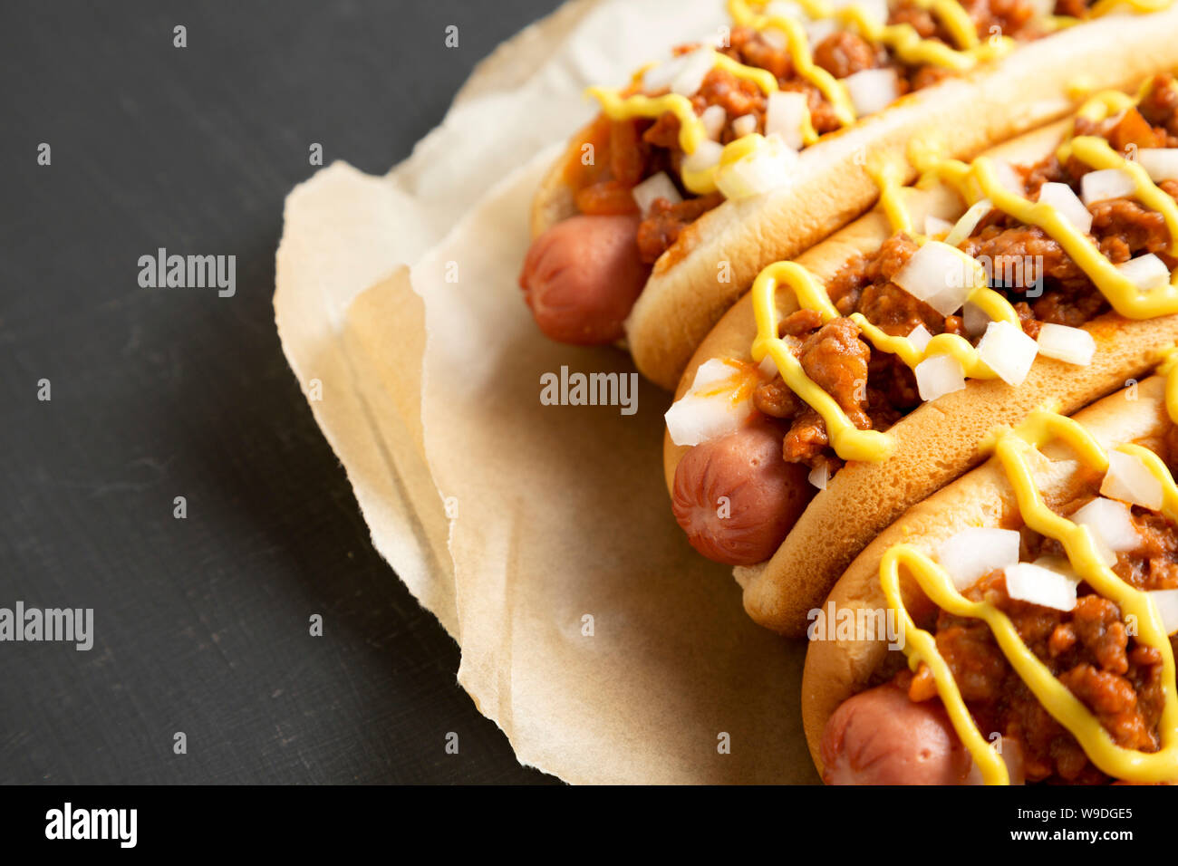 Homemade Detroit style chili dog on a black surface, side view. Copy ...