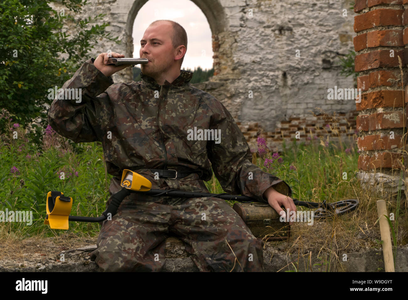 man treasure hunter sitting in the ruins of a building with a metal ...