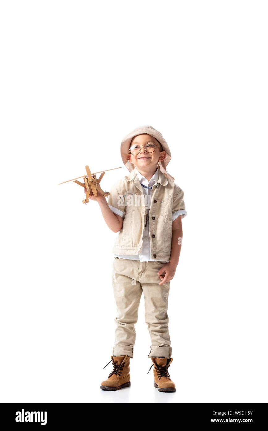full length view of smiling explorer boy in glasses and hat holding ...