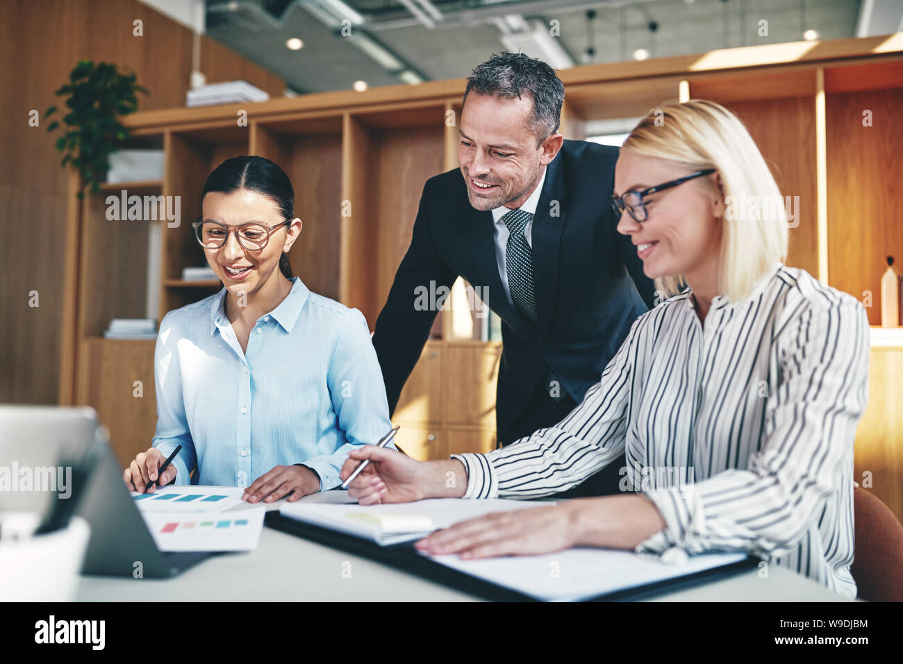 Group of smiling businesspeople going over paperwork together during a ...
