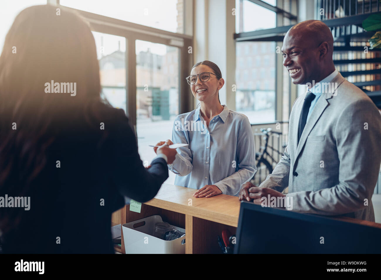 Two smiling guests giving their reservation details to a concierge ...