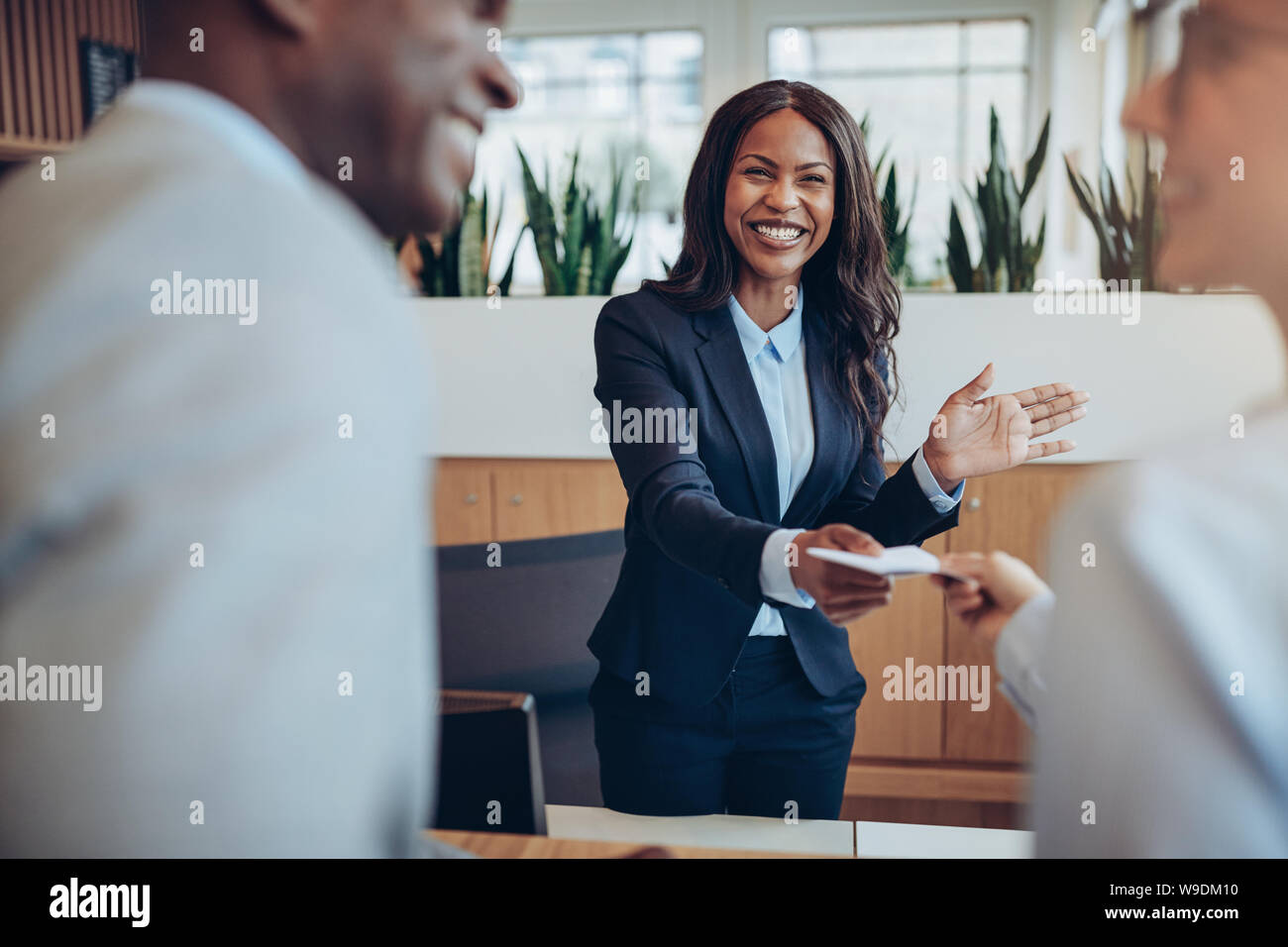 Friendly young African American concierge standing behind a reception ...