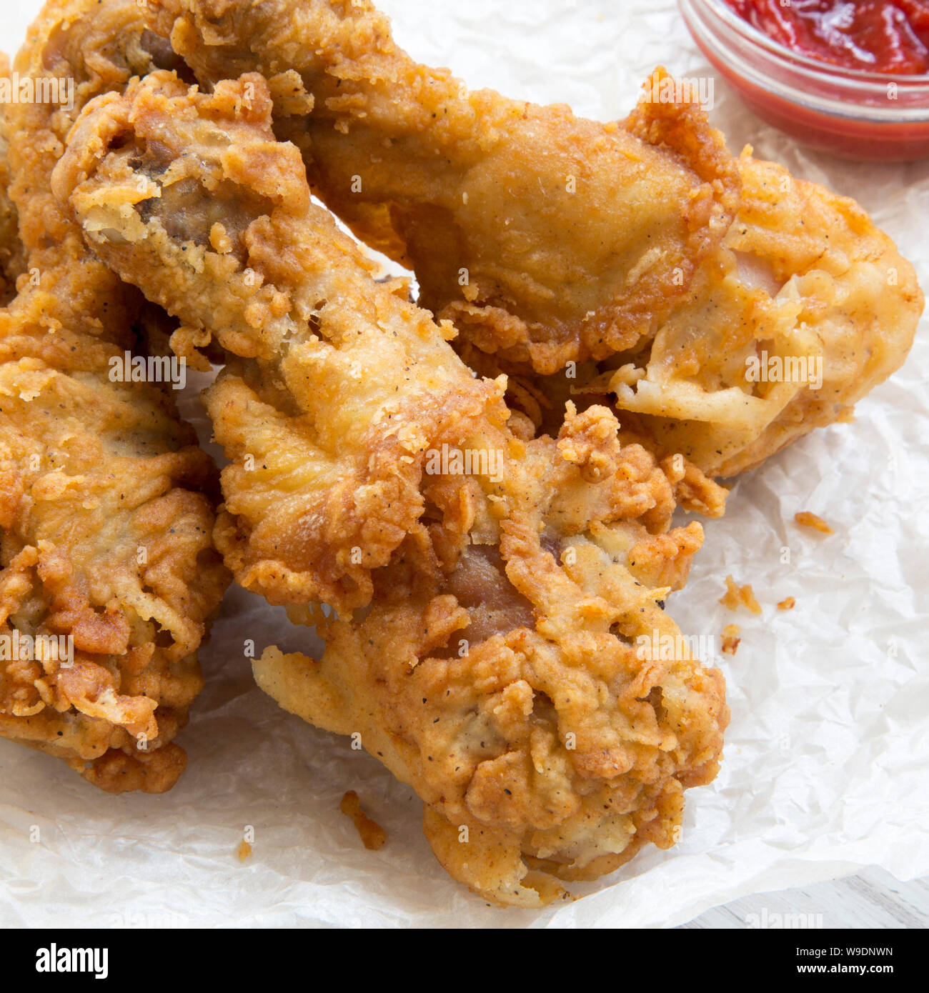 Fried chicken drumsticks with sauce, side view. Closeup Stock Photo - Alamy
