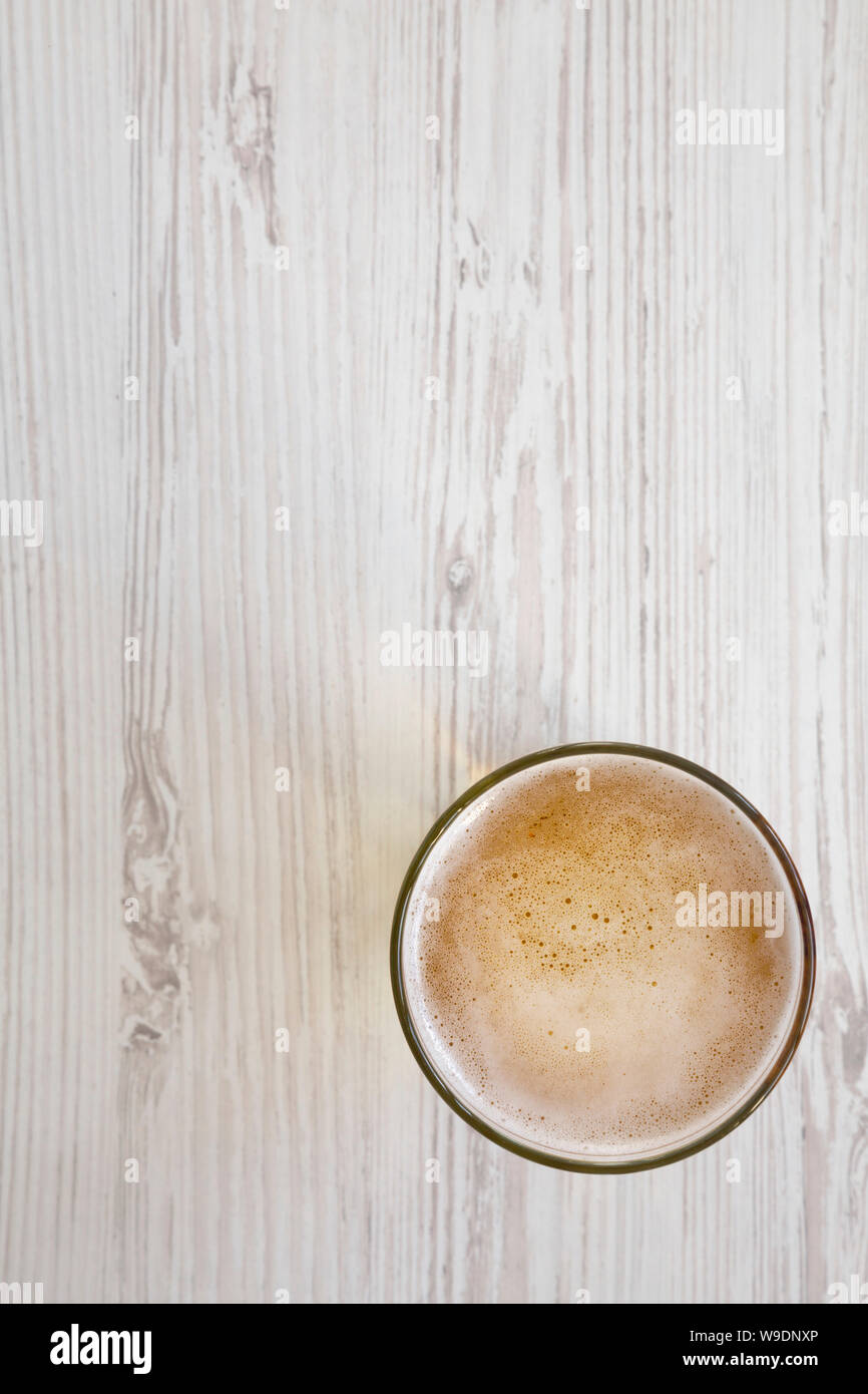 Glass of light beer on a white wooden background, top view. Overhead ...