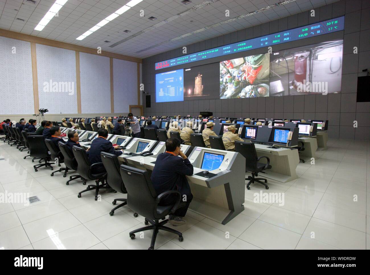 Chinese aeronautical scientists, workers and commanders look at screens ...