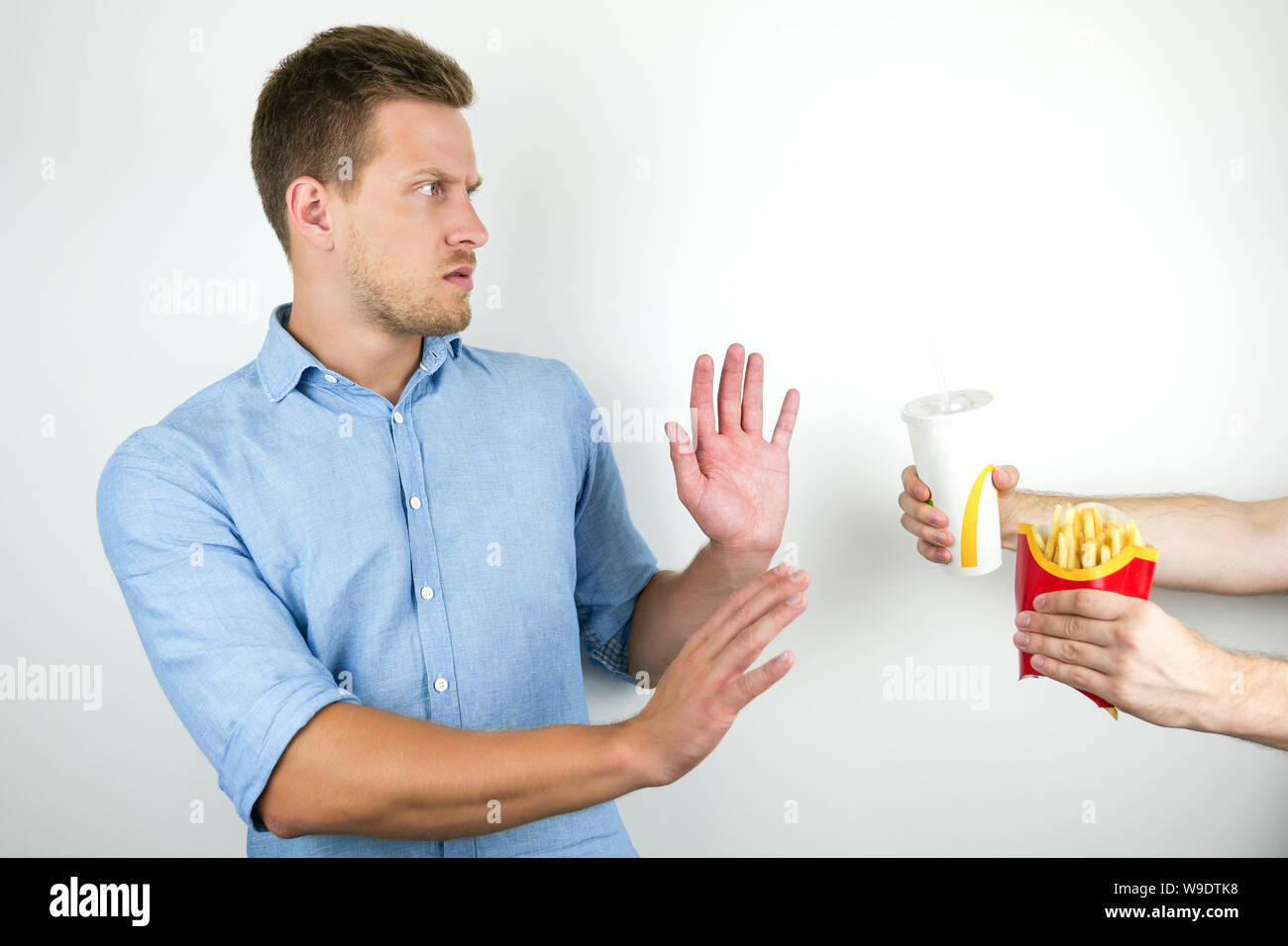 young handsome man refuses to eat fast food french fries and drink soda ...