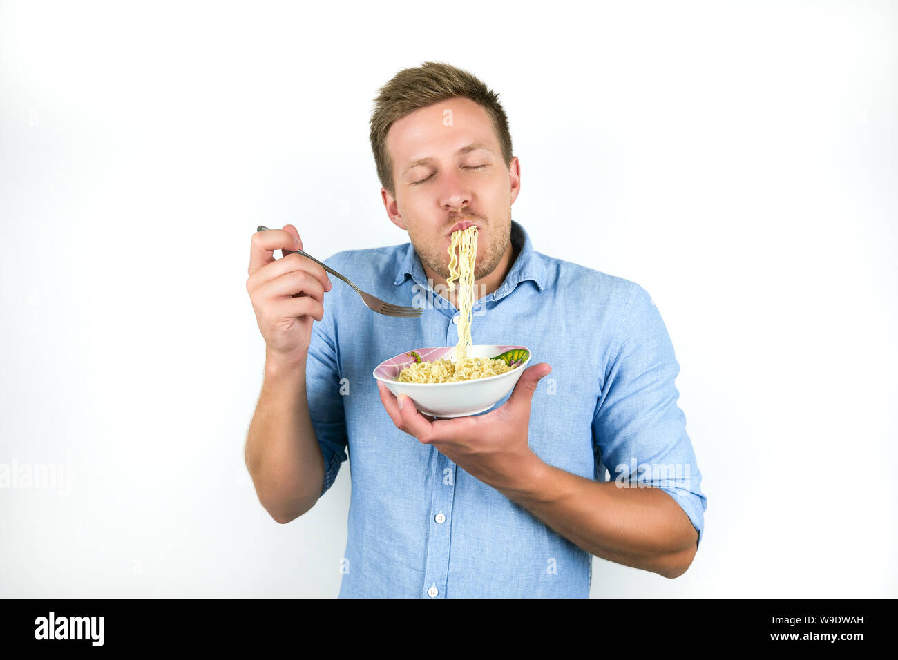 young handsome man eating noodles looks hungry on isolated white ...