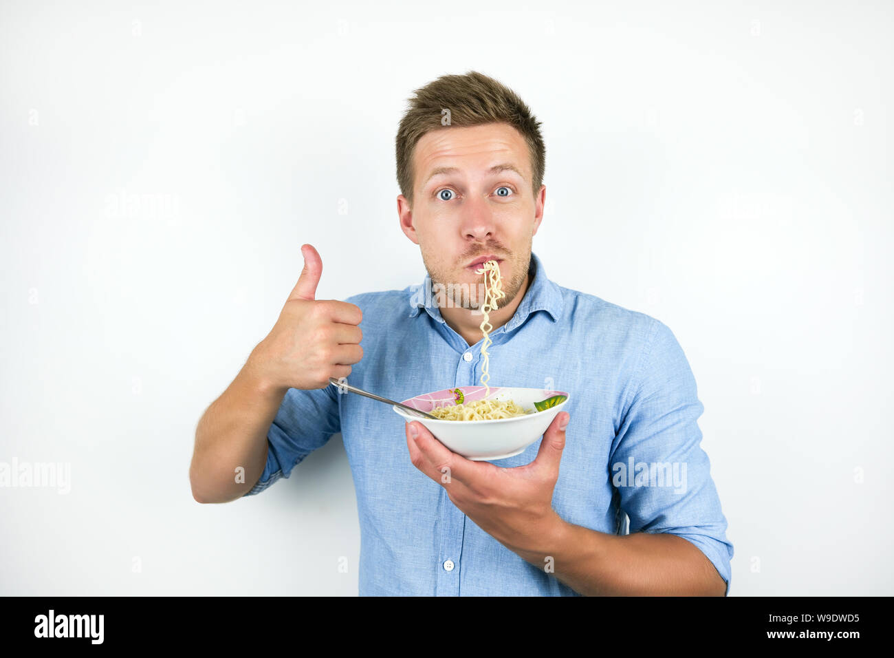 young handsome man eating noodles showing like sign on isolated white ...