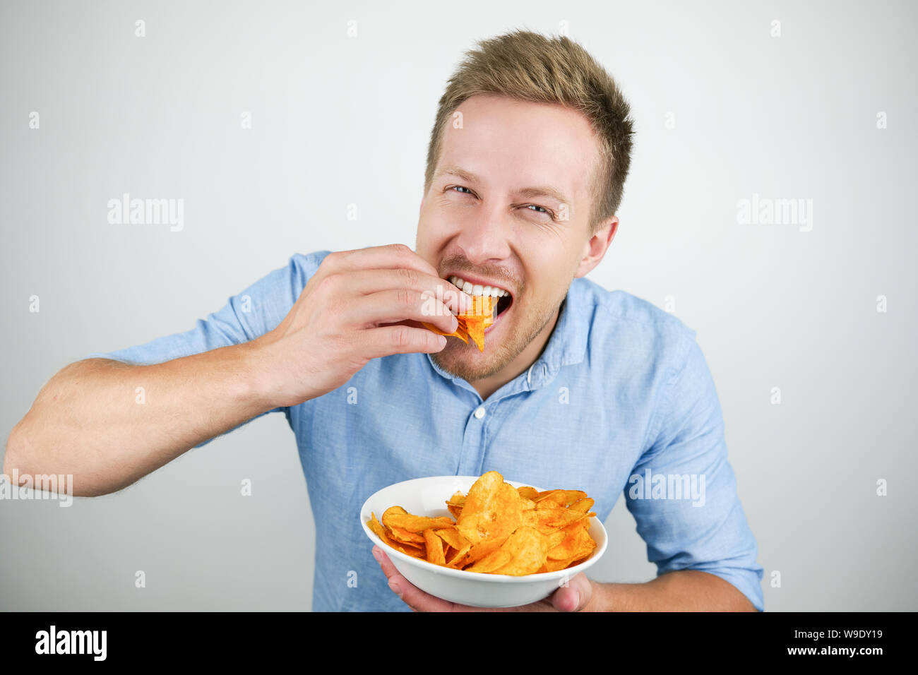 young handsome man eats chips on isolated white background Stock Photo ...