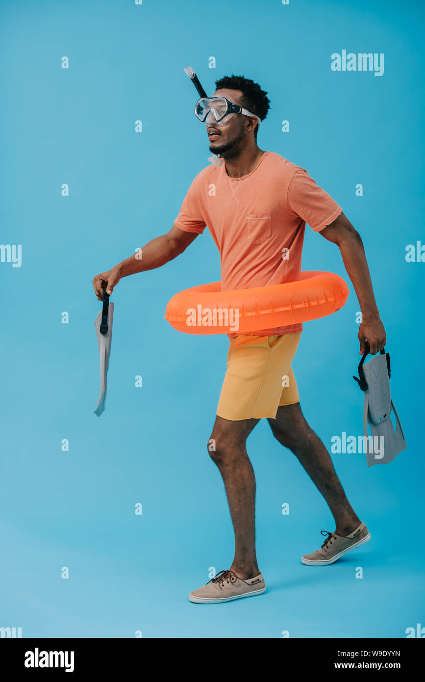 african american man in diving mask holding flippers and walking on ...