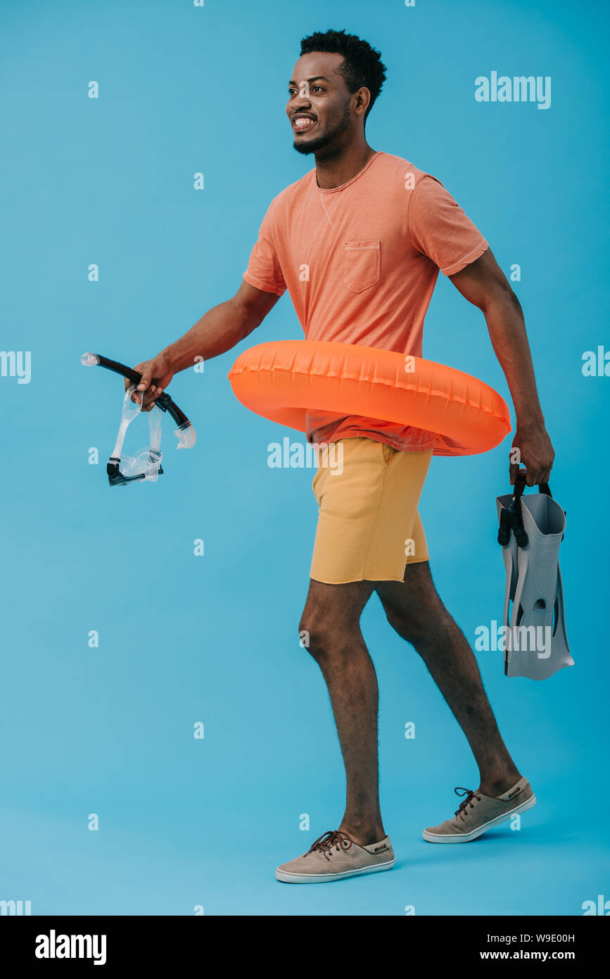 happy african american man in diving mask holding flippers and walking ...