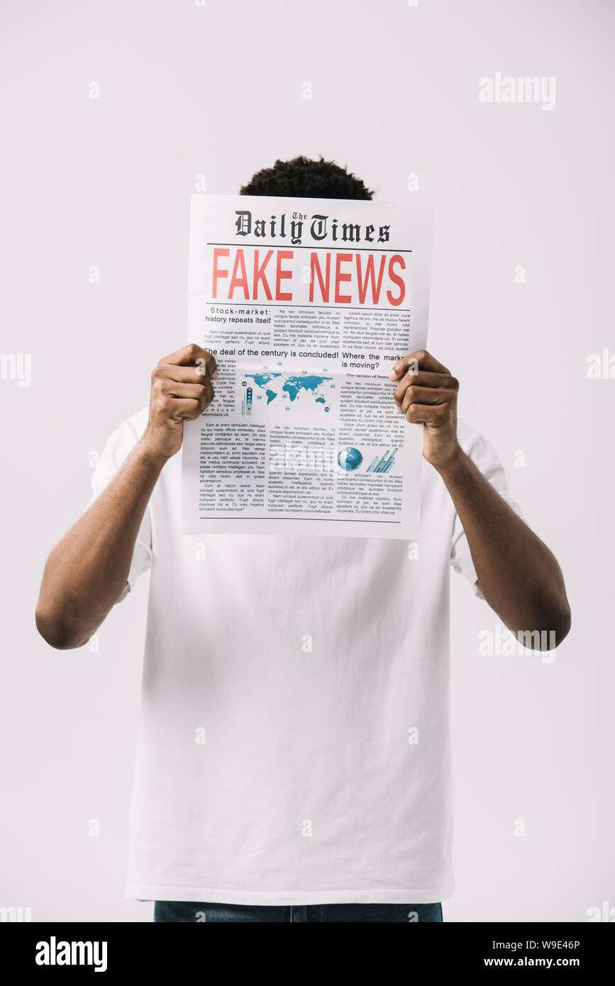 african american man covering face while reading newspaper with fake ...