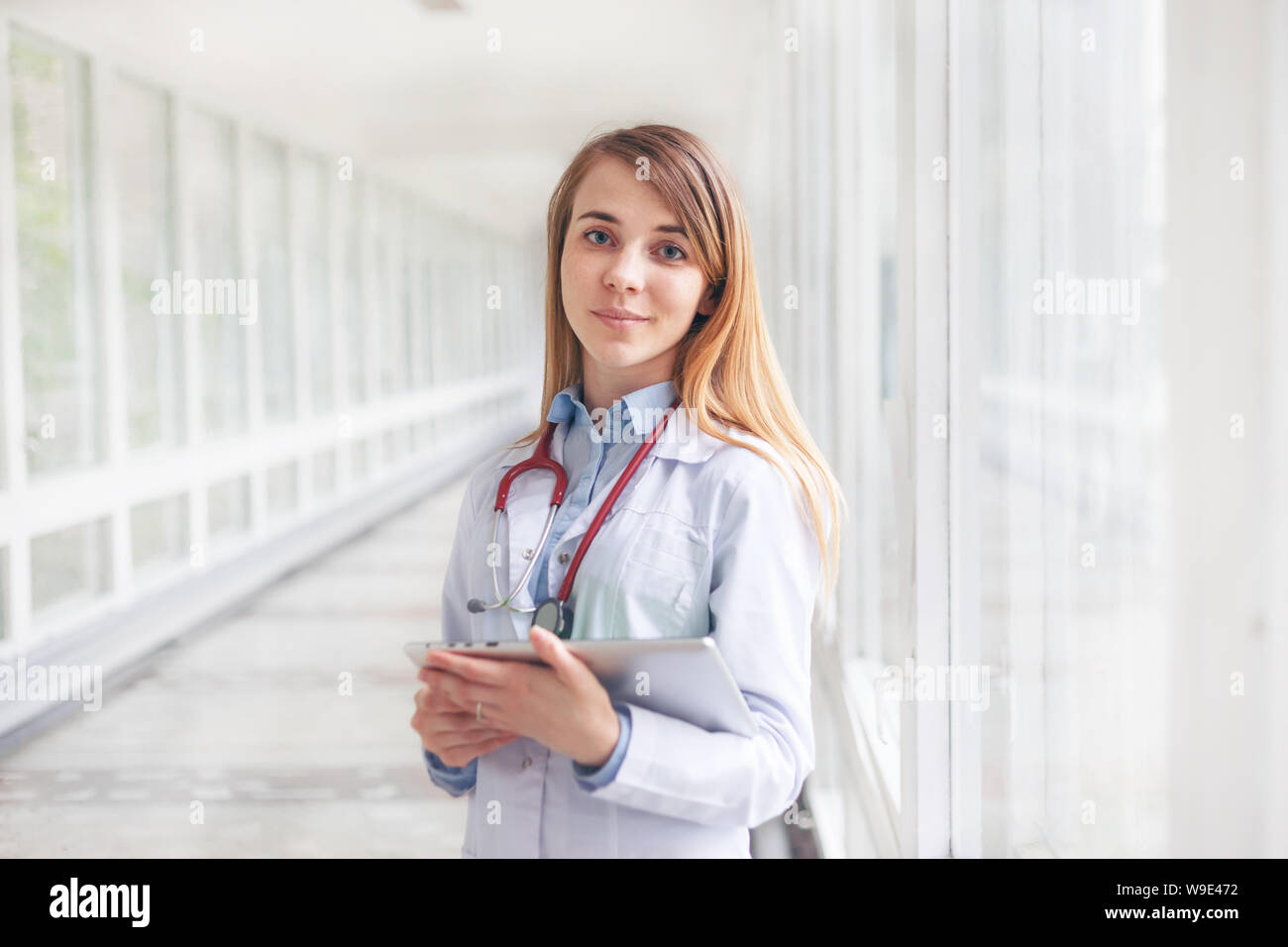 beautiful young female medical intern with tablet computer in office ...