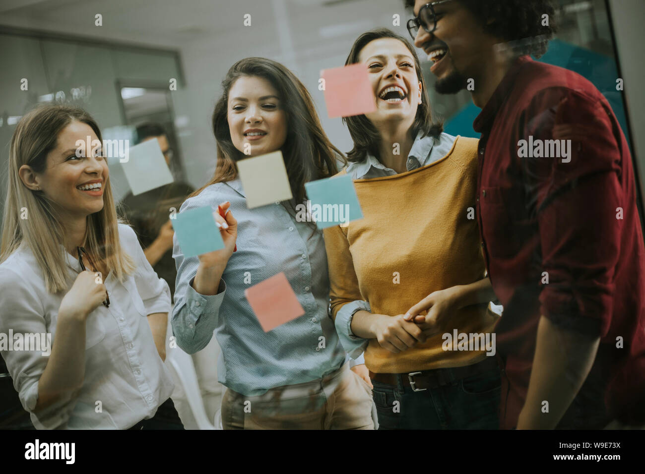 Group of young business people discussing in front of glass wall using ...