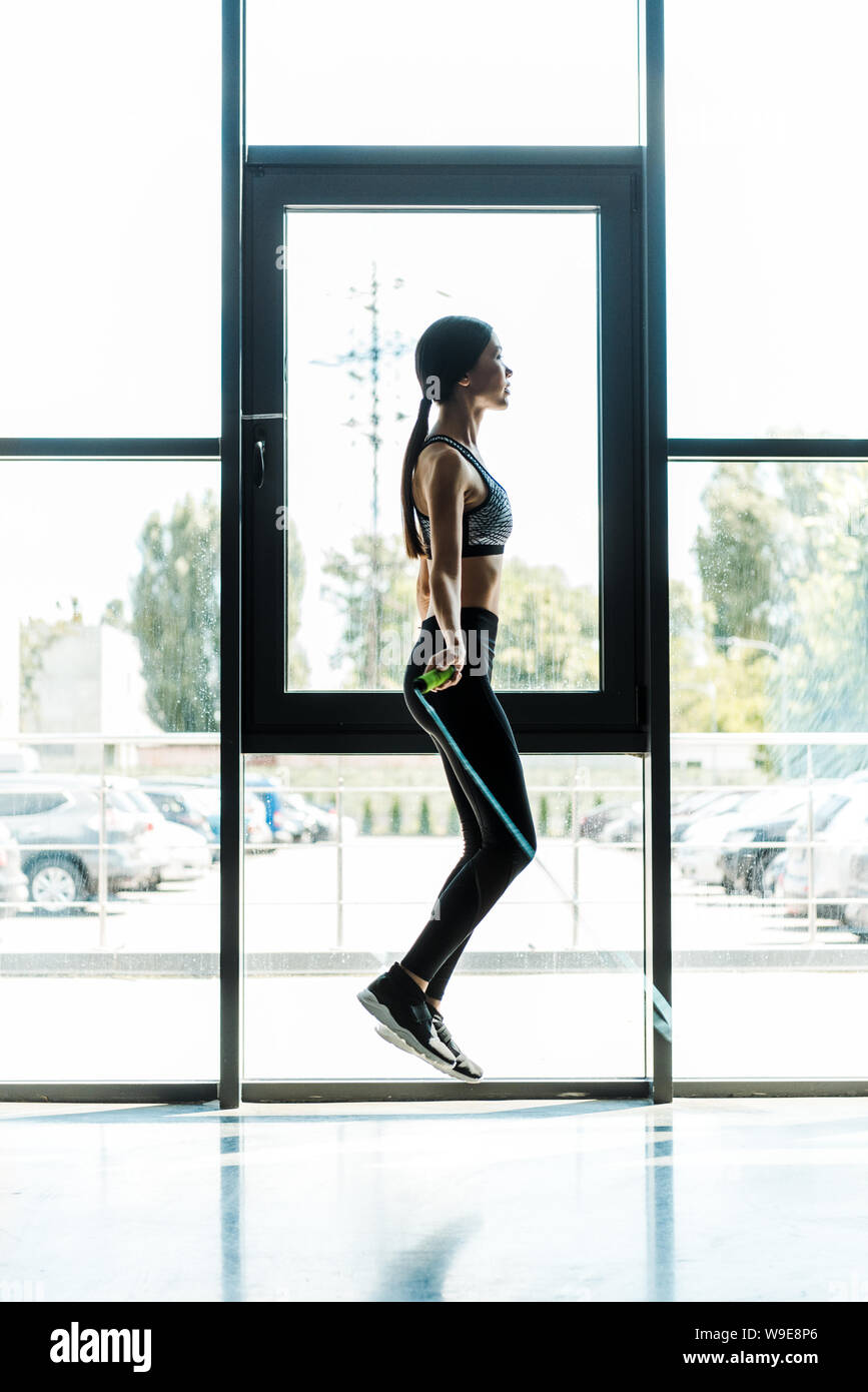 side view of attractive young woman jumping with skipping rope Stock ...