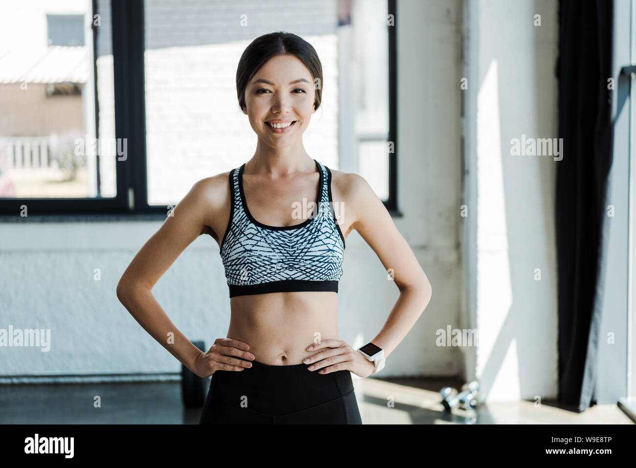 happy young woman standing with hands on hips in gym Stock Photo - Alamy