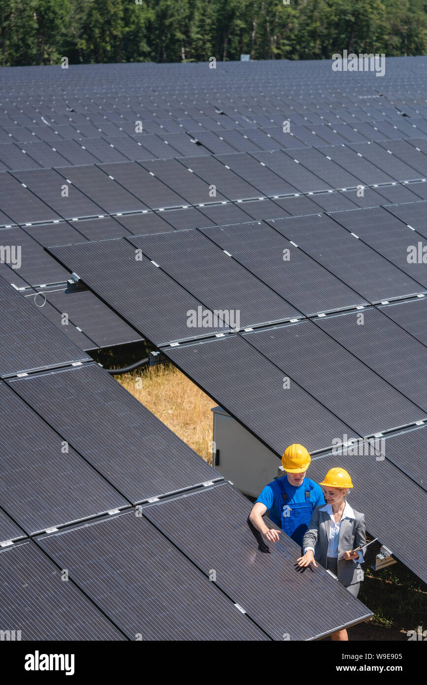 Two people standing amid solar cells in a power plant Stock Photo - Alamy