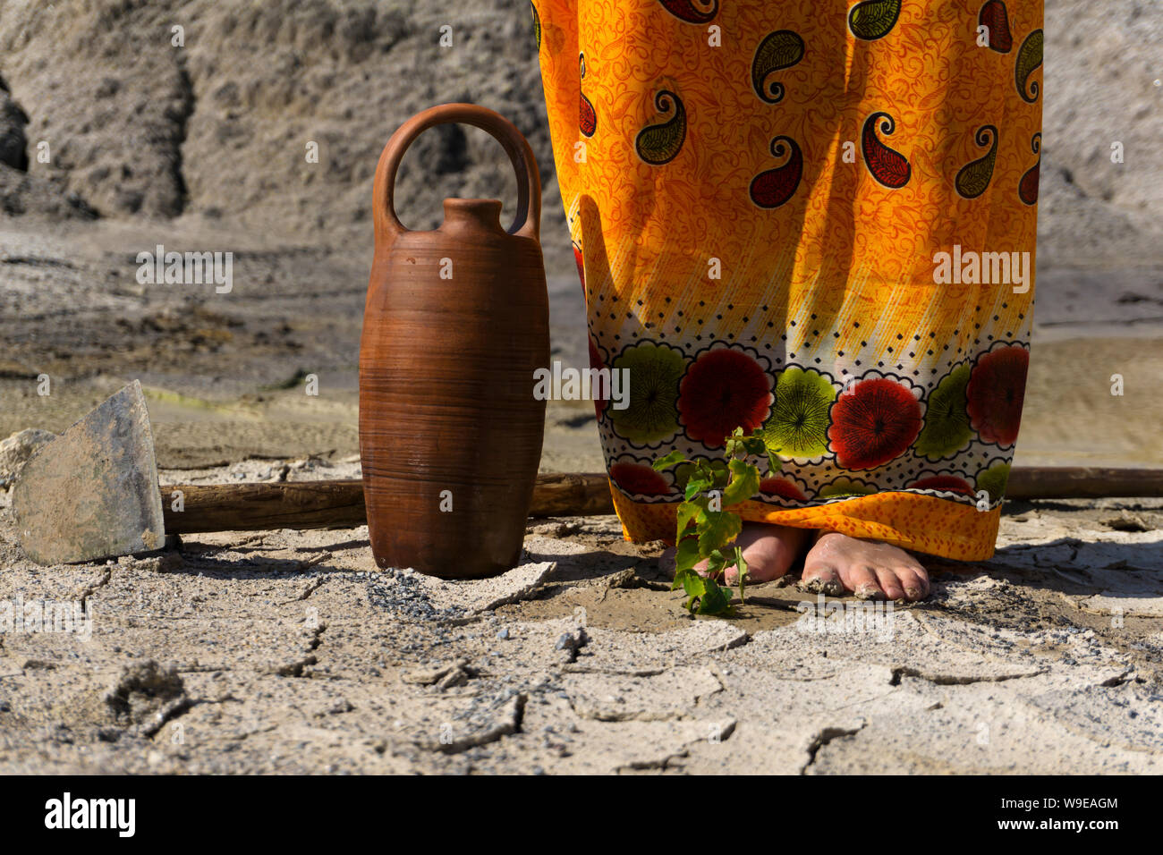 small sprout in the desert at the feet of a woman in ethnic clothing ...