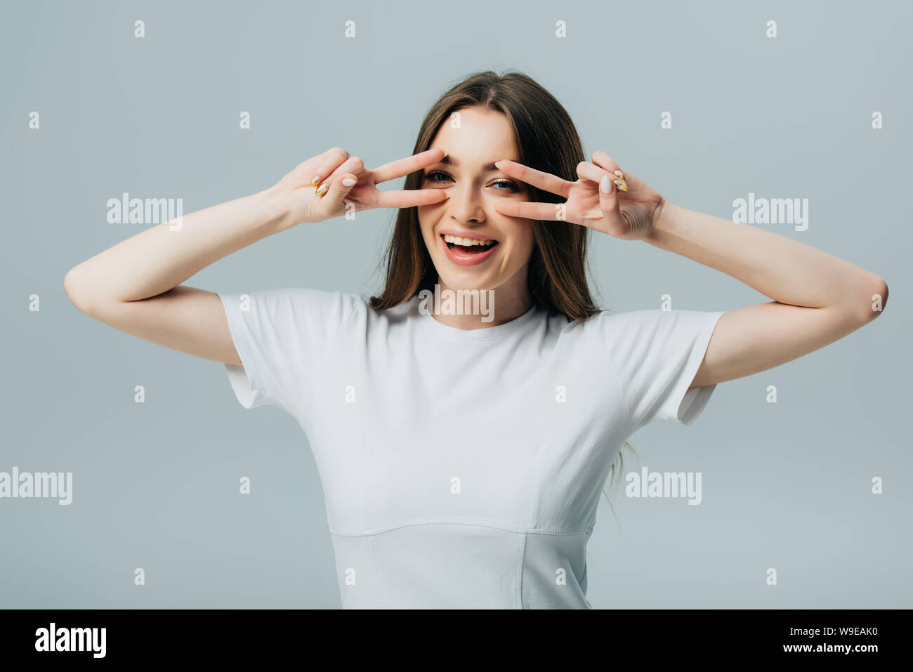 beautiful happy girl showing peace signs isolated on grey Stock Photo ...