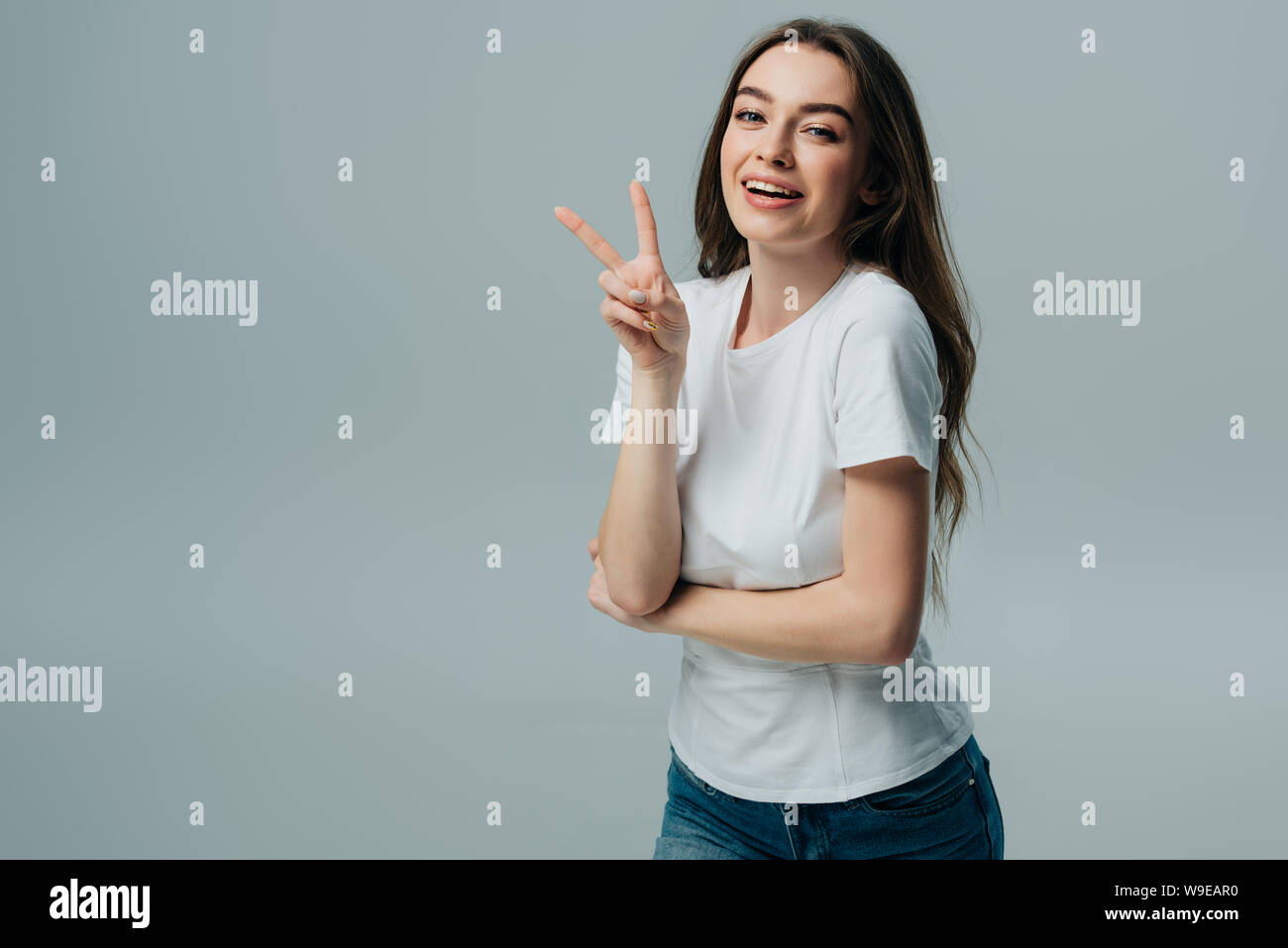 beautiful happy girl showing peace sign isolated on grey Stock Photo ...