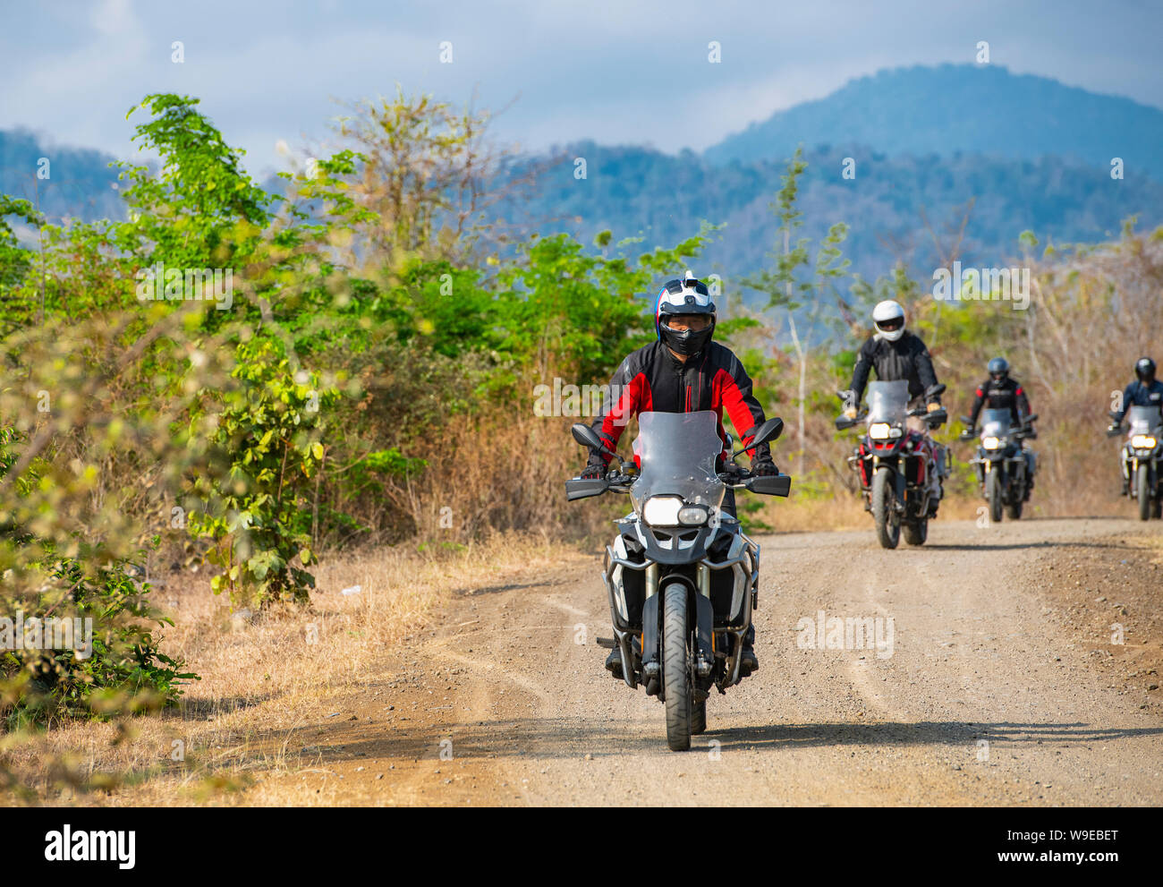 group of men riding their ADV motorbikes on gravel road in Cambodia ...