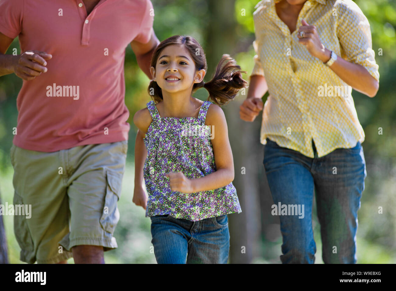 Parents chasing their playful young daughter through the park Stock ...
