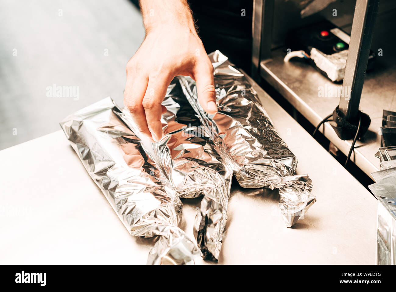 cropped view of man and doner kebabs in aluminium foil Stock Photo - Alamy