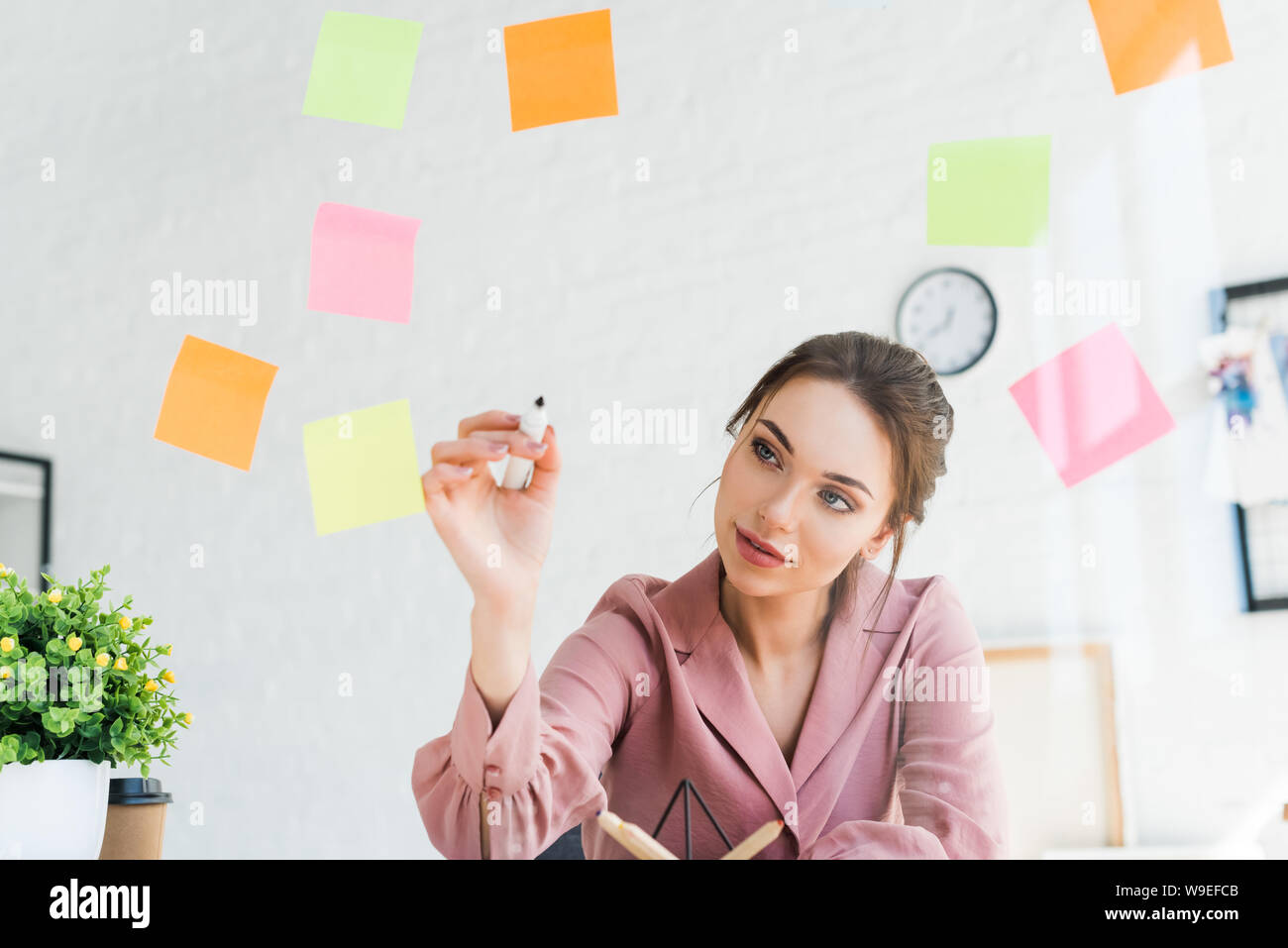 attractive young woman writing on window with sticky notes Stock Photo ...