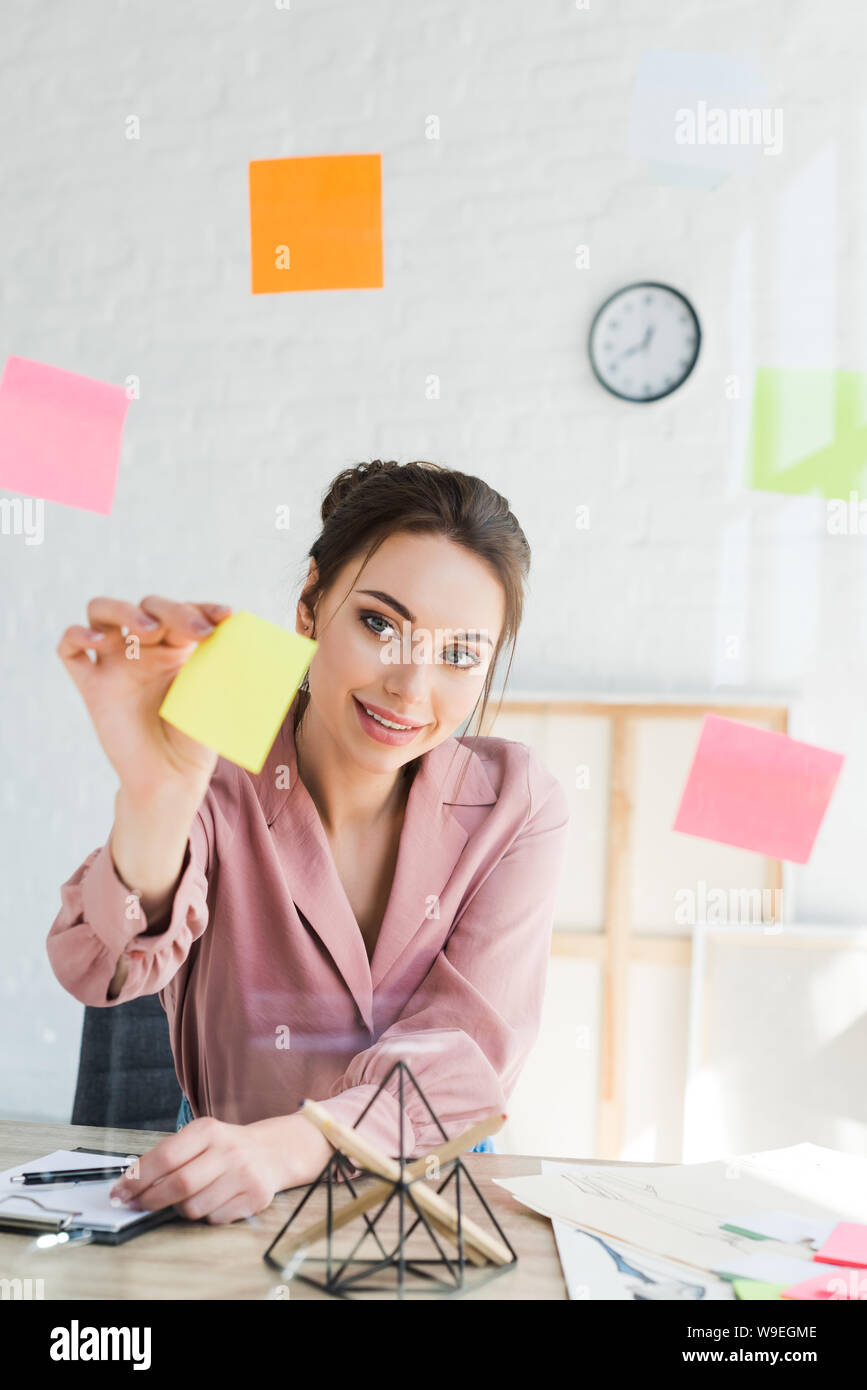 attractive young woman hanging sticky note on window Stock Photo - Alamy