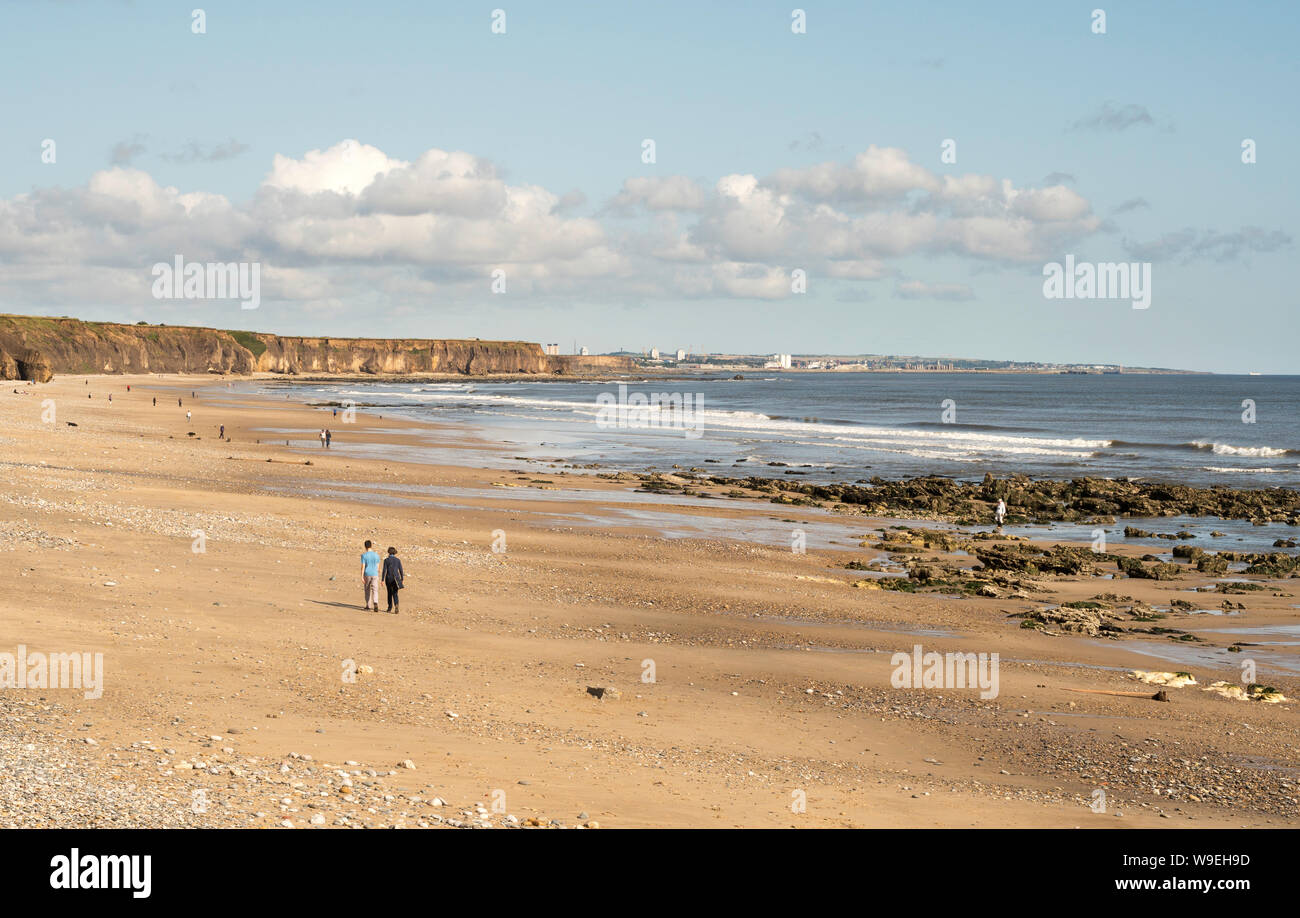 Couple walking on Seaham North Beach with Sunderland in the distance ...