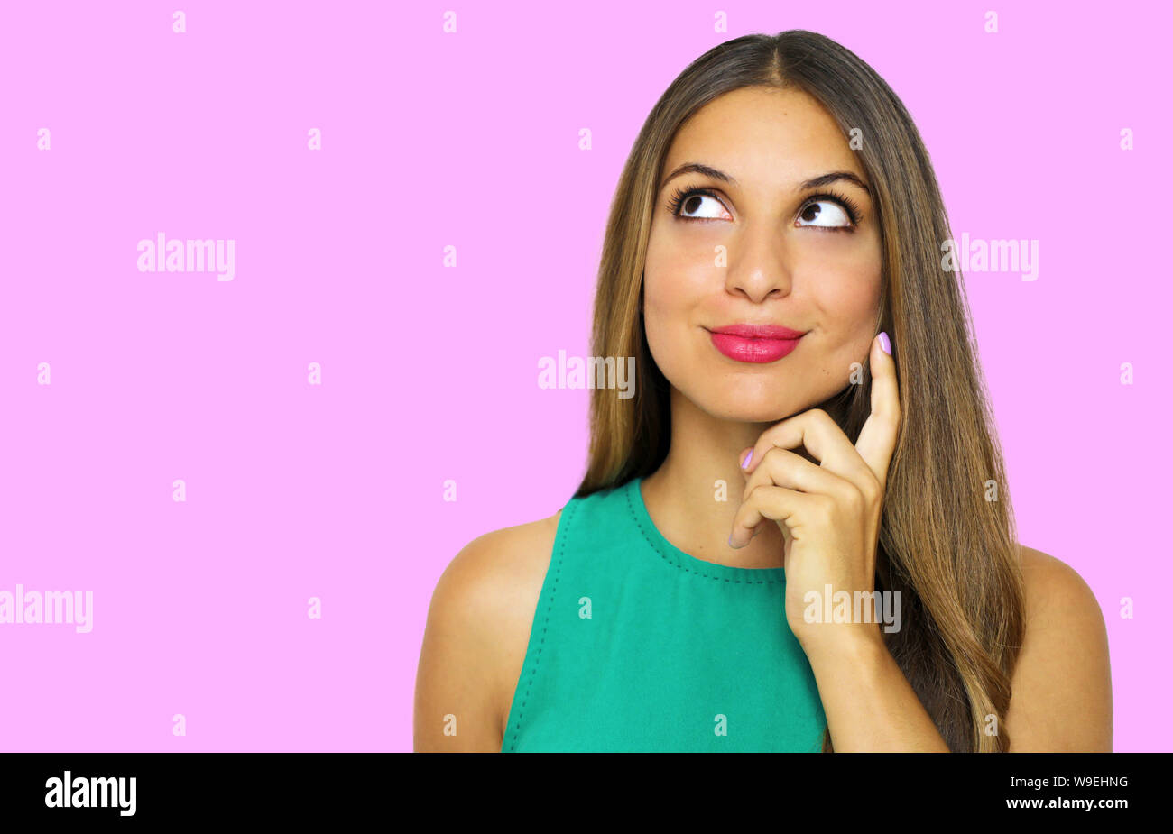 Studio portrait of beautiful young woman thinking and looking upwards ...