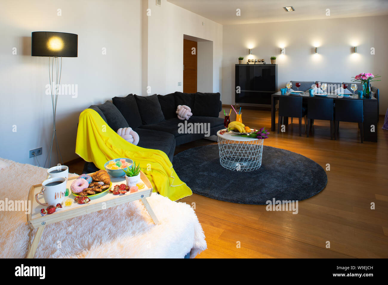 Living room in studio apartment. Grey sofa. Served table. Laid tray ...