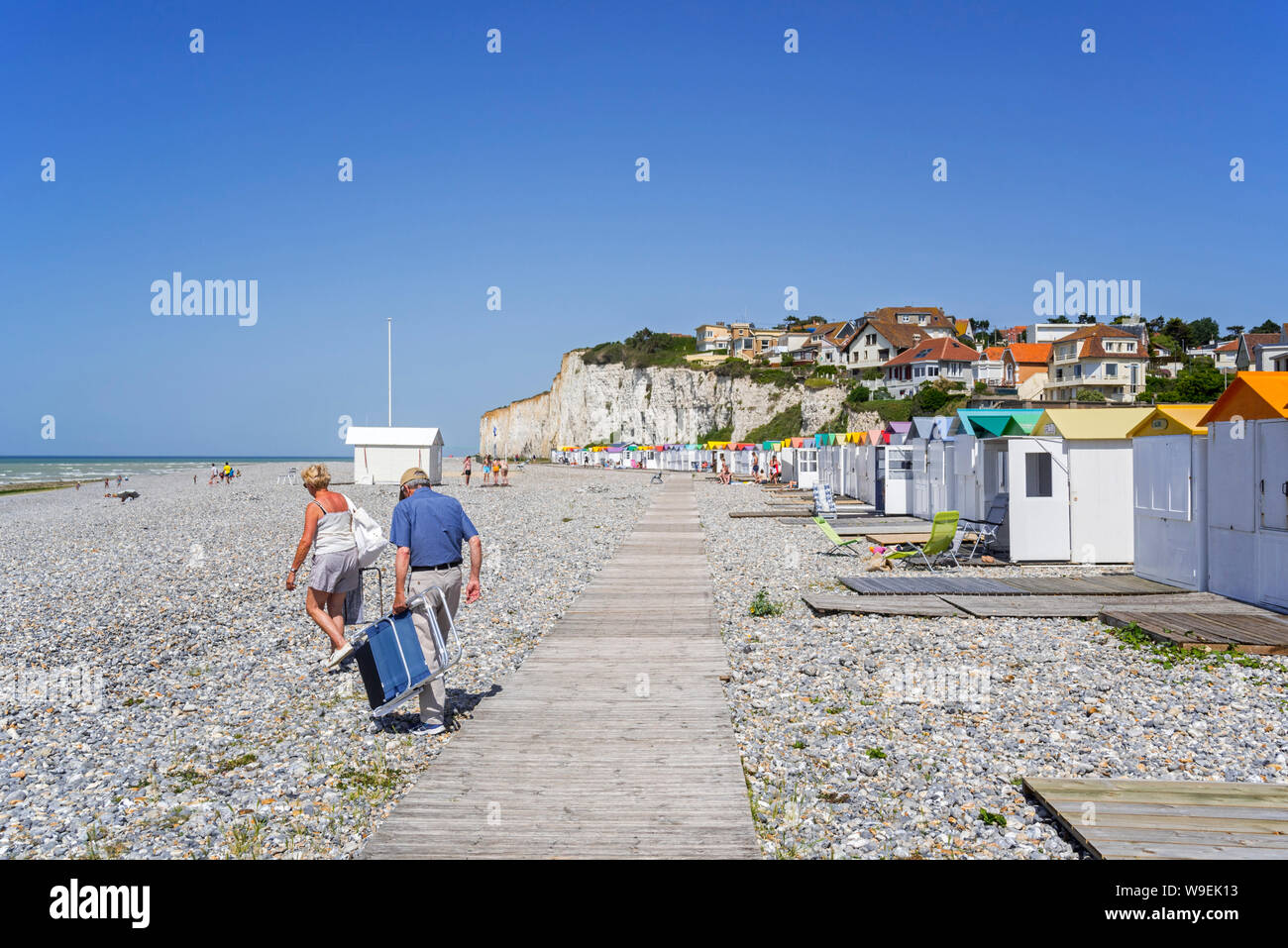 Sunbathers and colourful beach cabins on shingle beach / pebble beach ...