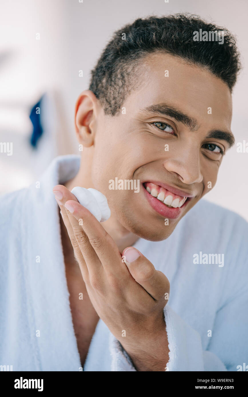 portrait shot of handsome man applying shaving cream on face while ...
