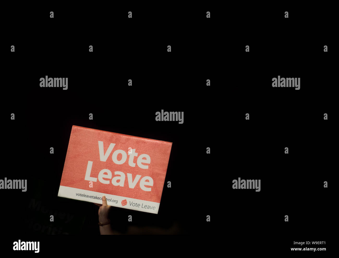 A person holding an isolated Vote Leave sign on simple dark bakground ...
