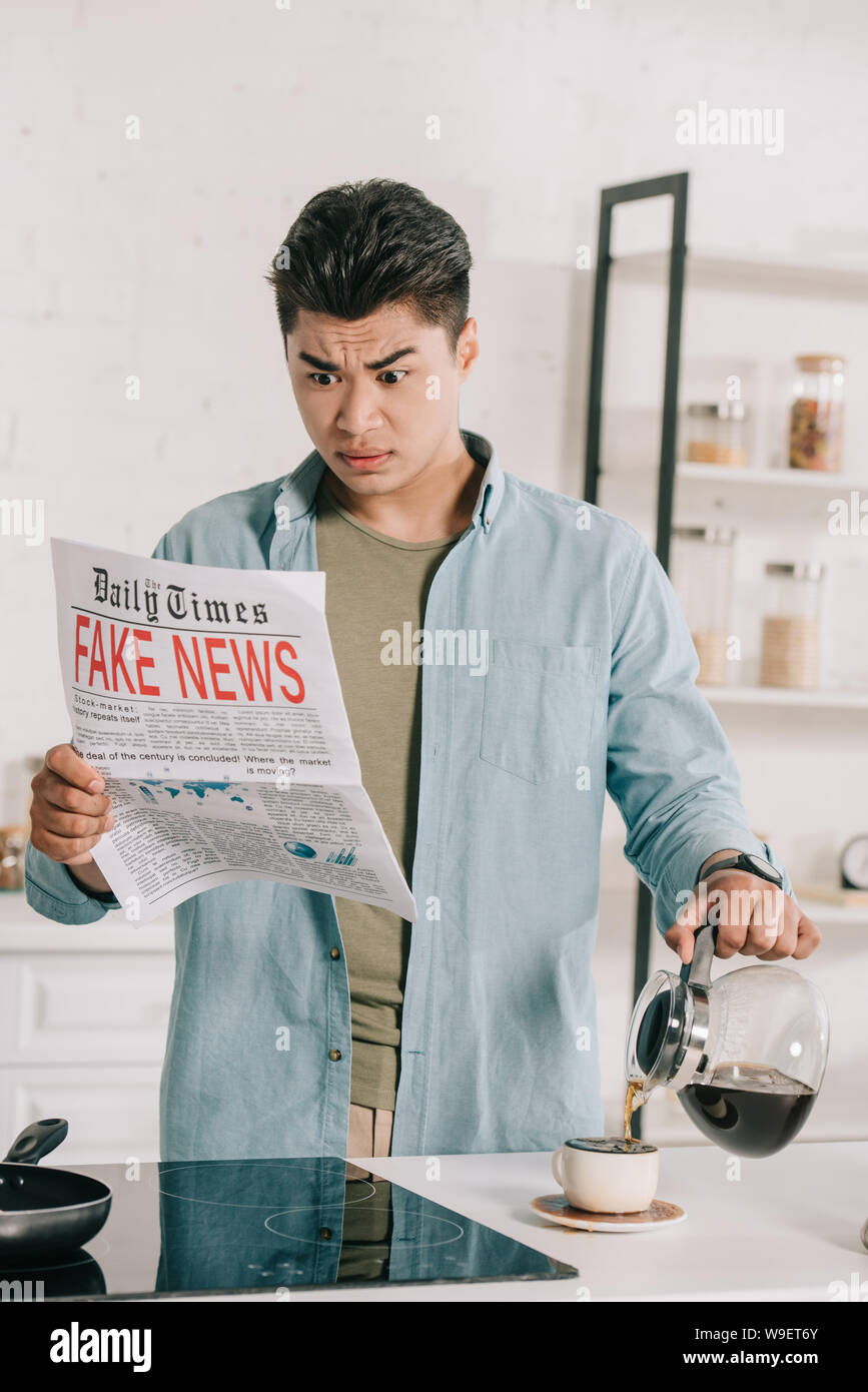 shocked asian man reading fake news newspaper while pouring coffee in ...