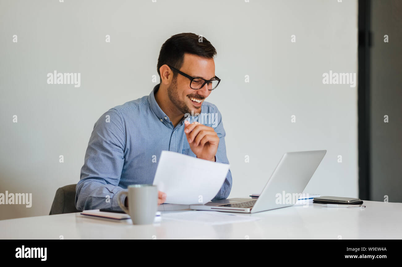 Young smiling cheerful businessman in office on video conference call ...