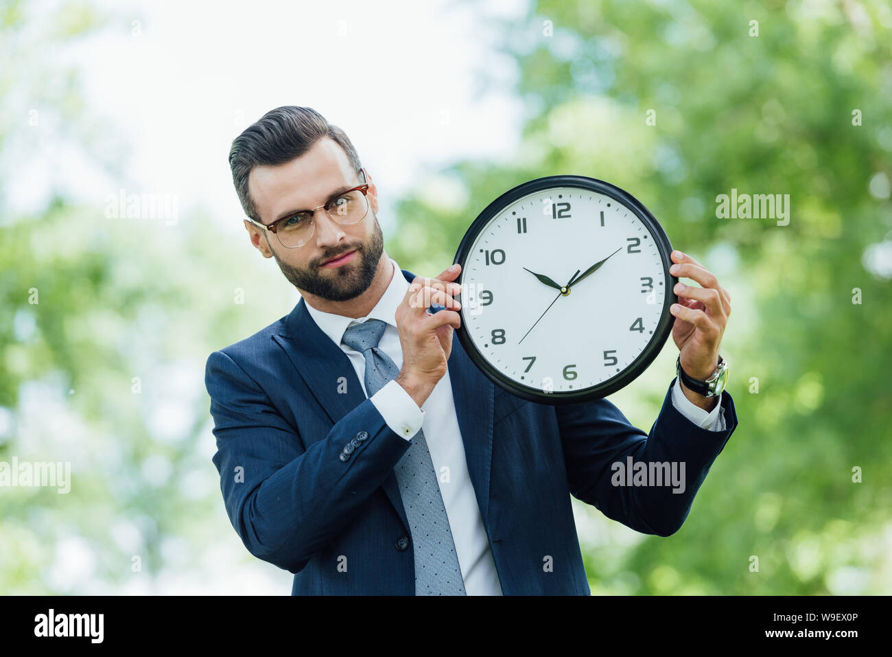 Young businessman holding clock hi-res stock photography and images - Alamy